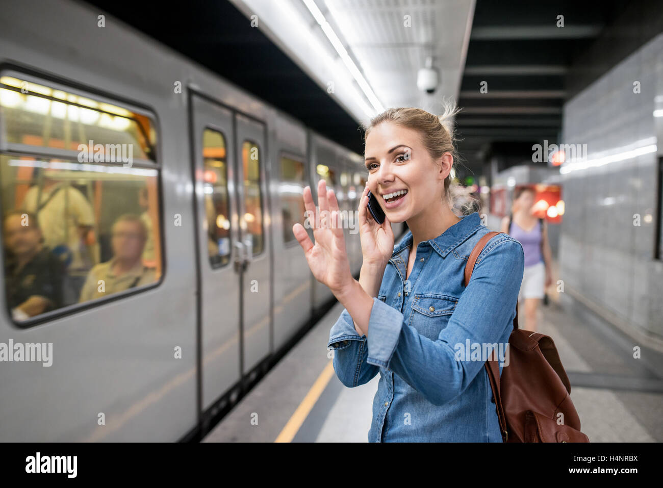 Woman making phone call at the underground platform, waving Stock Photo ...
