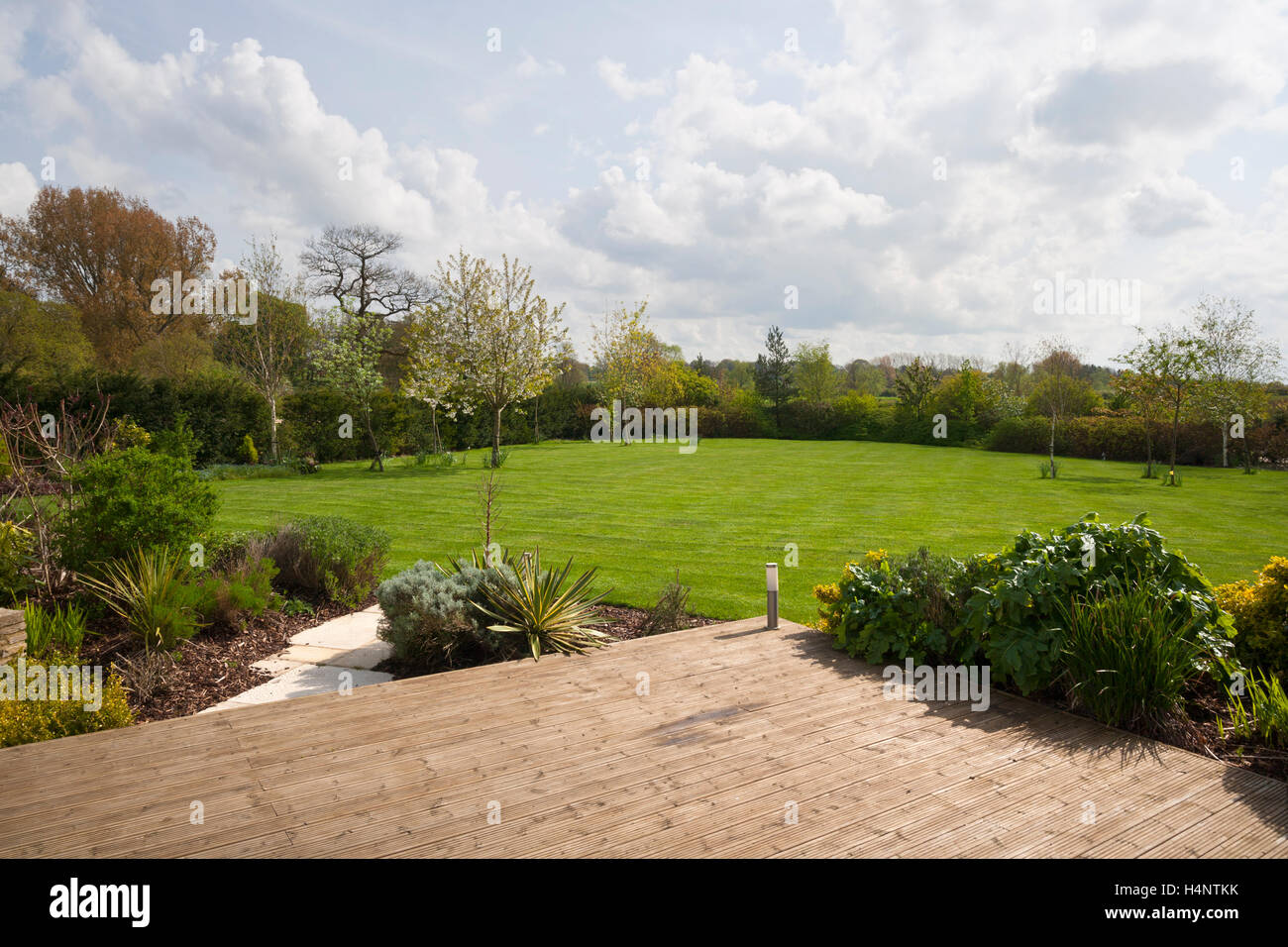 Decking with a large lawned garden with mower stripes and open ...