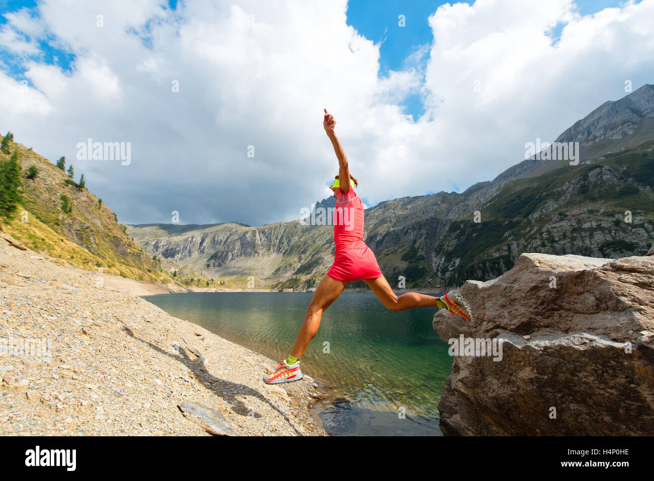 Woman with beautiful body tanned jumping from a rock near a mountain ...