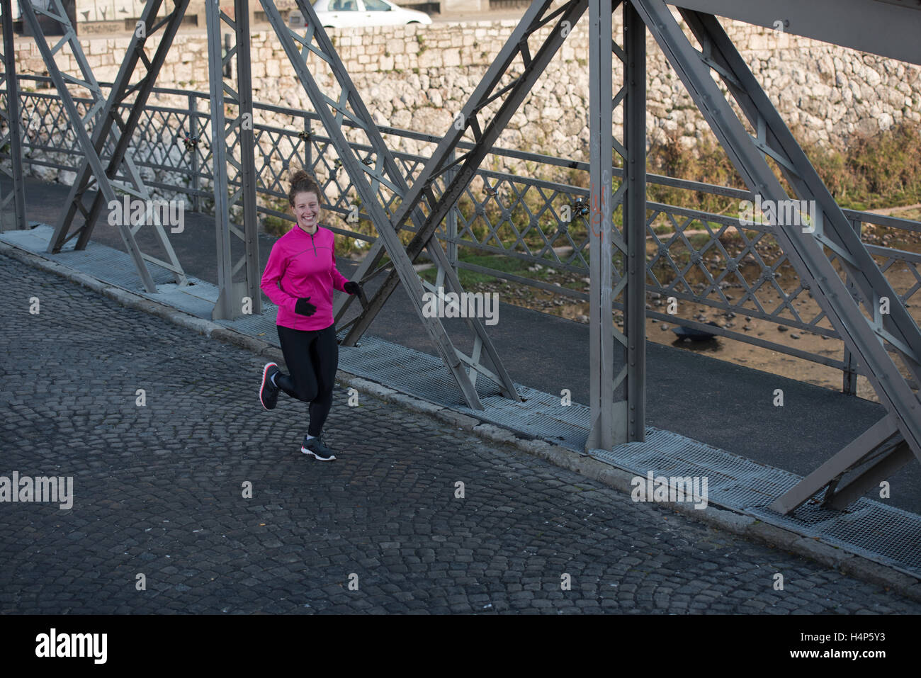 sporty woman running on sidewalk at early morning jogging with city ...