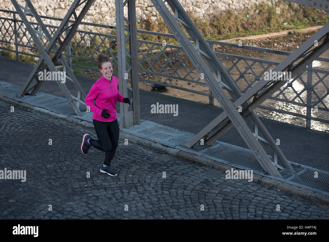 sporty woman running on sidewalk at early morning jogging with city ...