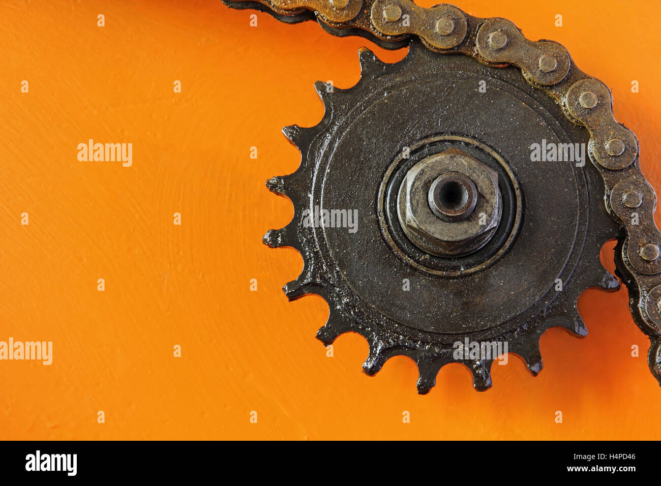 Metal cogwheel and chain on orange background Stock Photo - Alamy