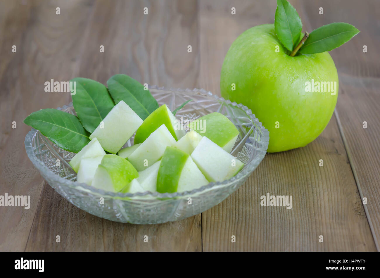 Ripe green apple with leaf and slice on a wooden background Stock Photo ...