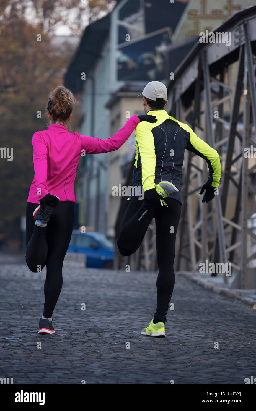 jogging couple warming up and stretching before morning running in the ...