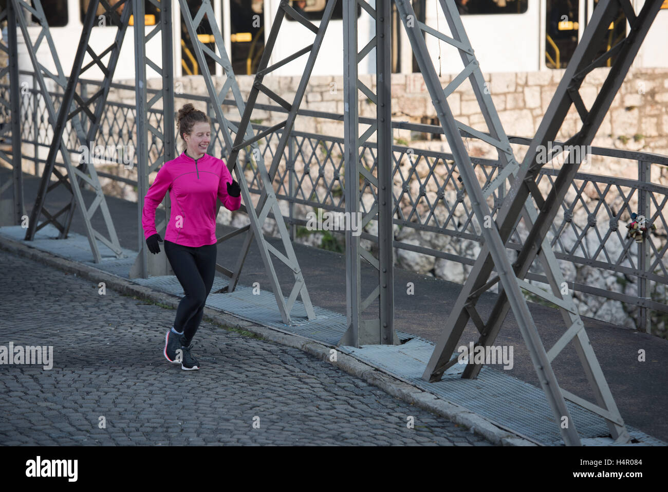 sporty woman running on sidewalk at early morning jogging with city ...