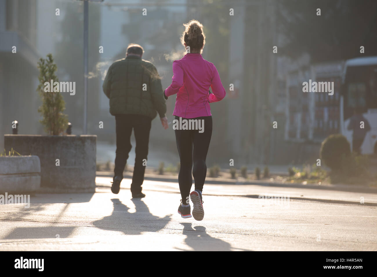 sporty woman running on sidewalk at early morning jogging with city ...