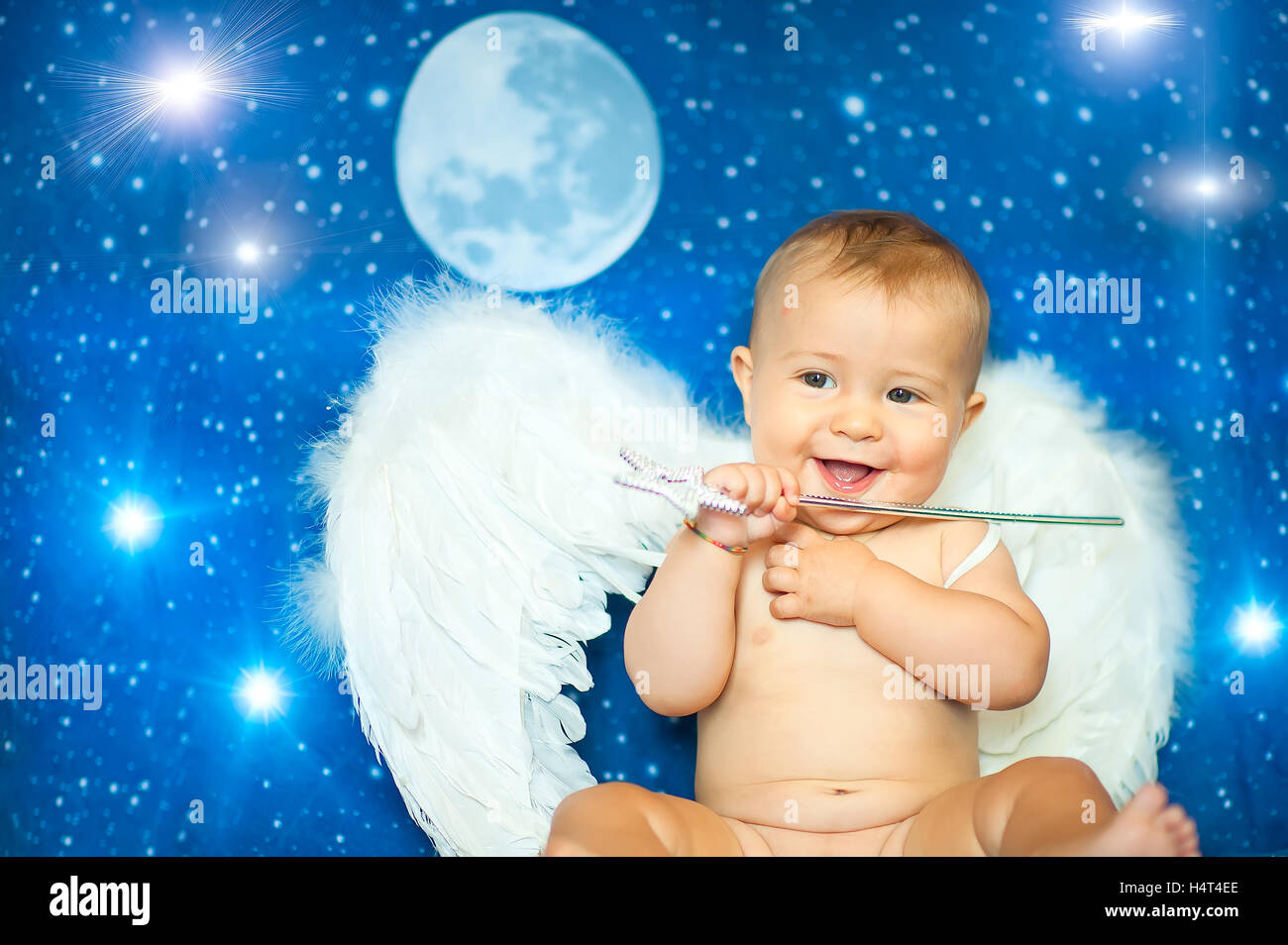 Baby a few months with magic wand and angel wings plays on us blue sky ...