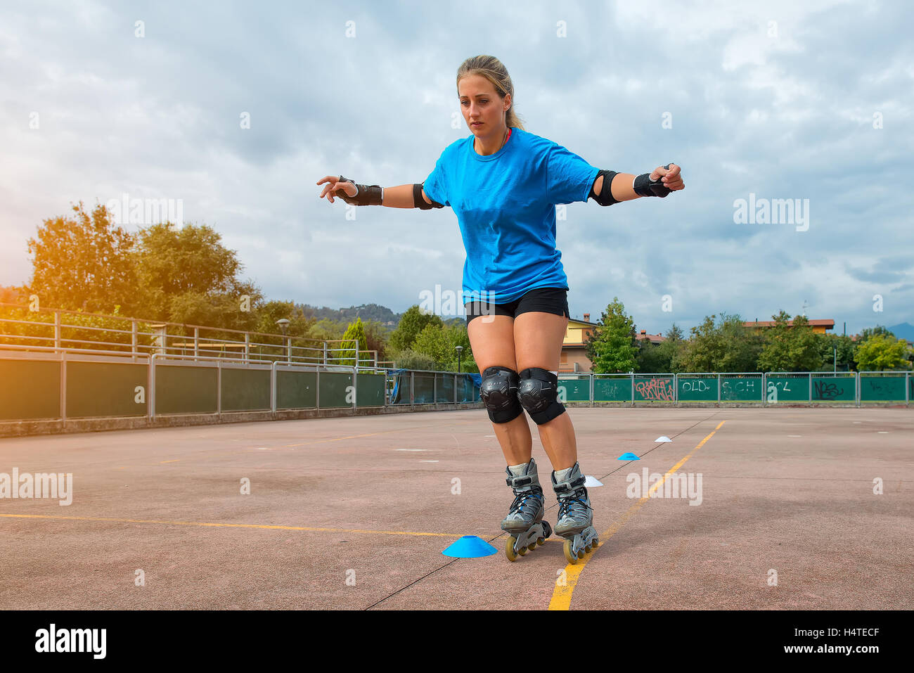 Blonde sports girl does slalom in a rollerblade field Stock Photo - Alamy
