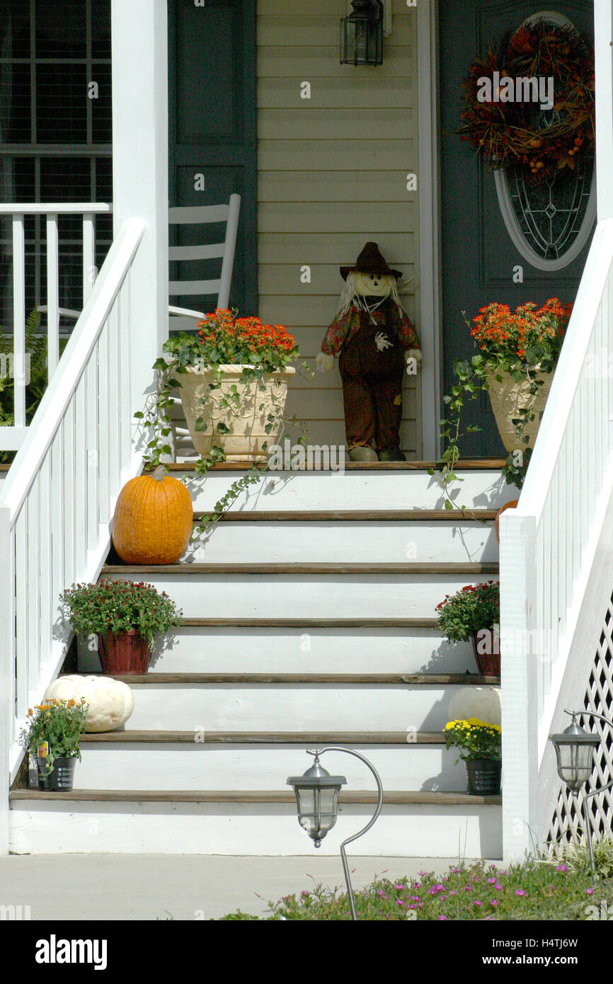 Scarecrows on the front porch with flower pots and pumpkins in the fall ...