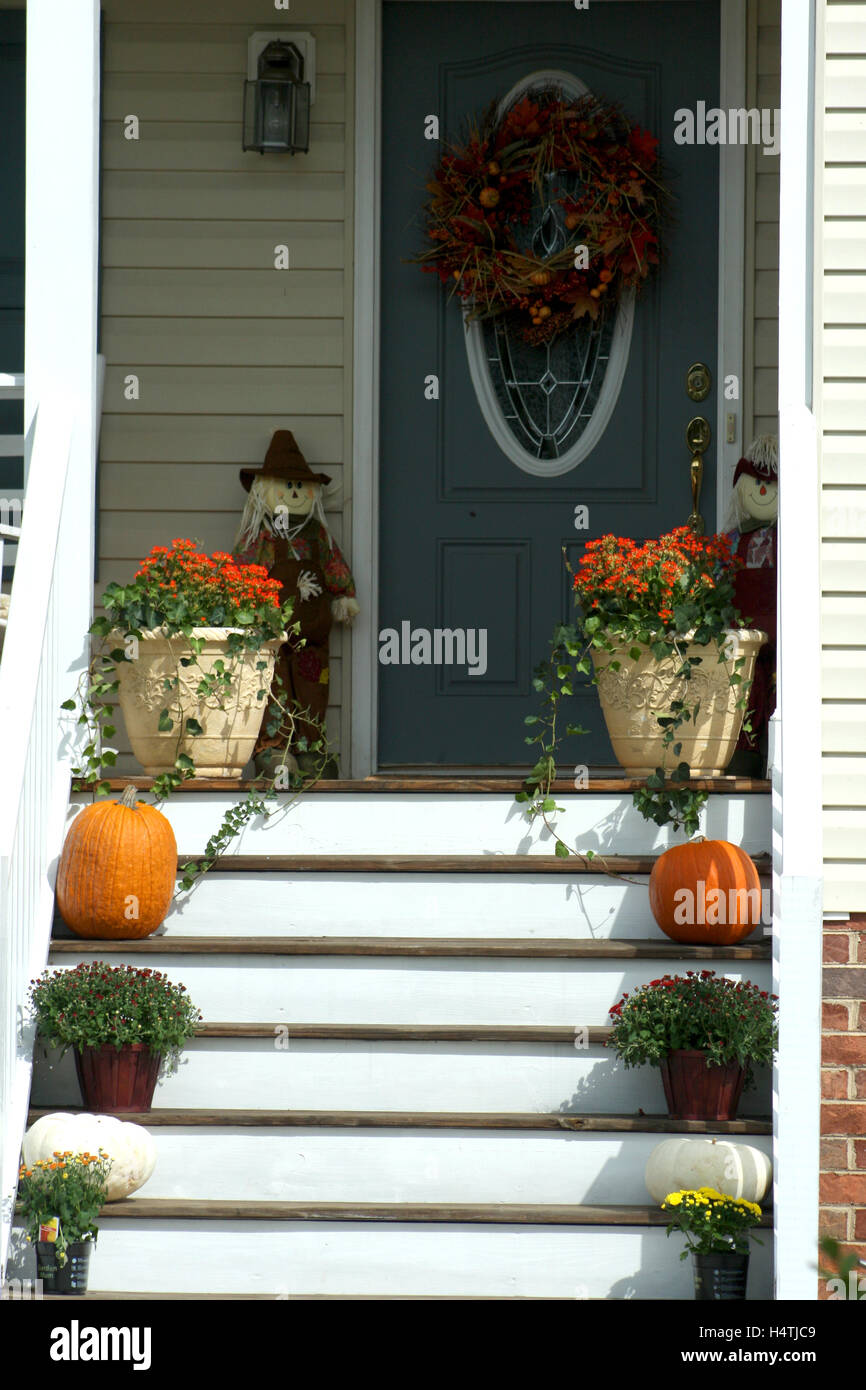 Scarecrows on the front porch with flower pots and pumpkins in the fall ...