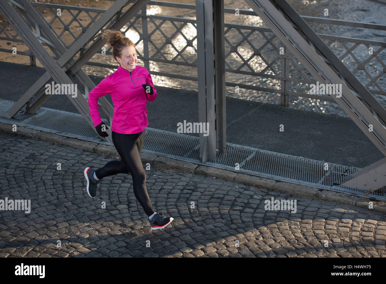 sporty woman running on sidewalk at early morning jogging with city ...