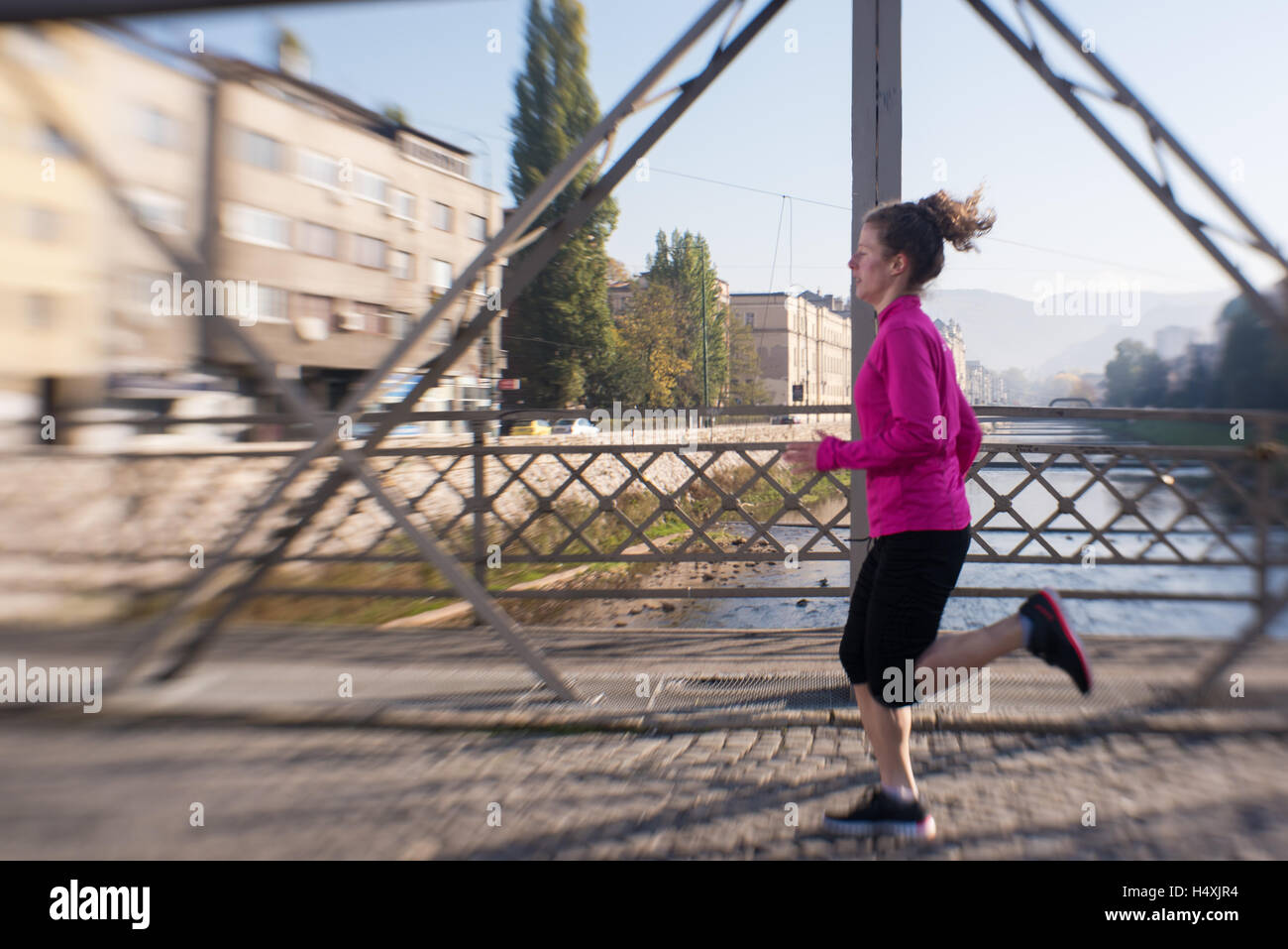 sporty woman running on sidewalk at early morning jogging with city ...