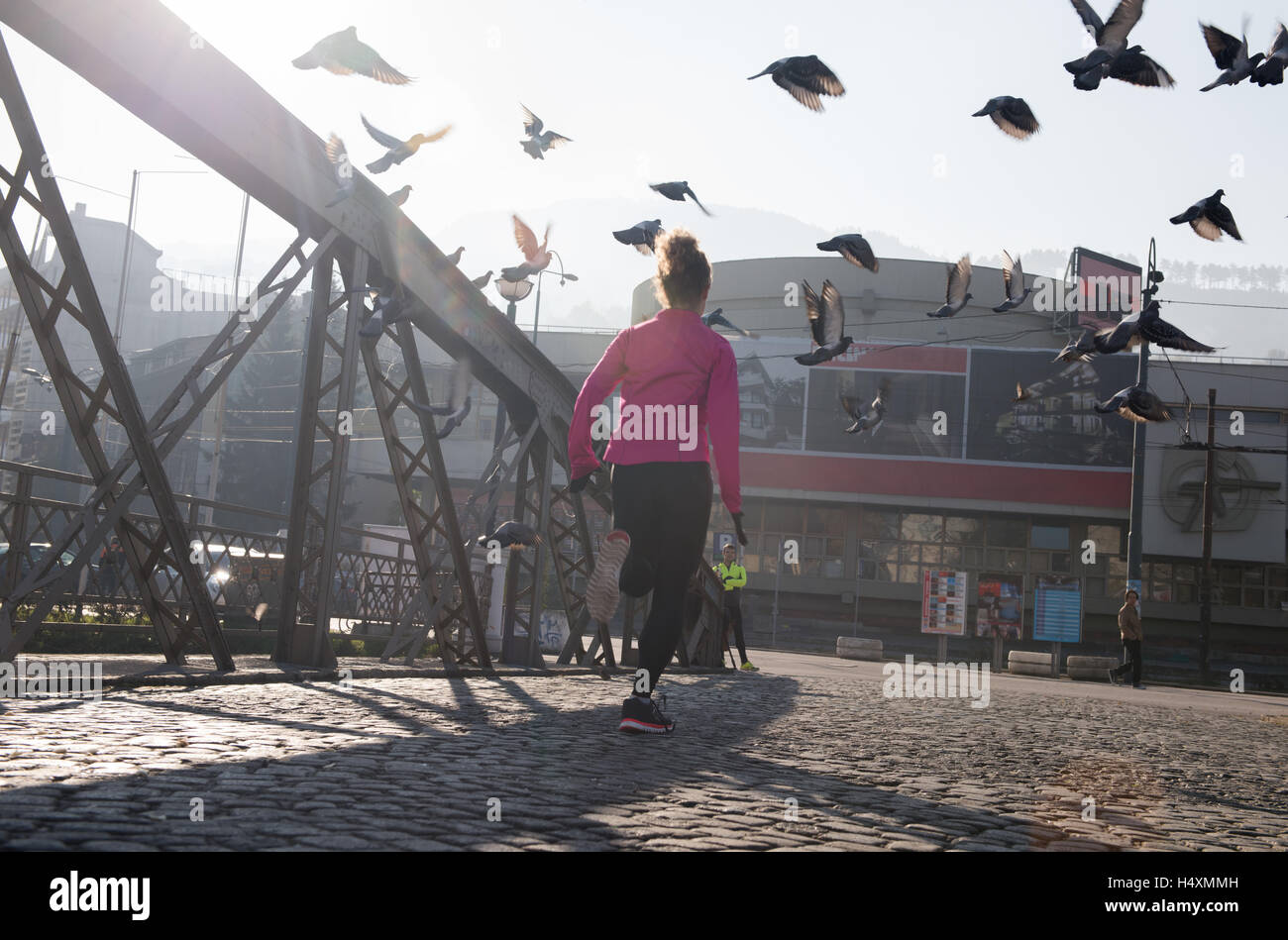 sporty woman running on sidewalk at early morning jogging with city ...