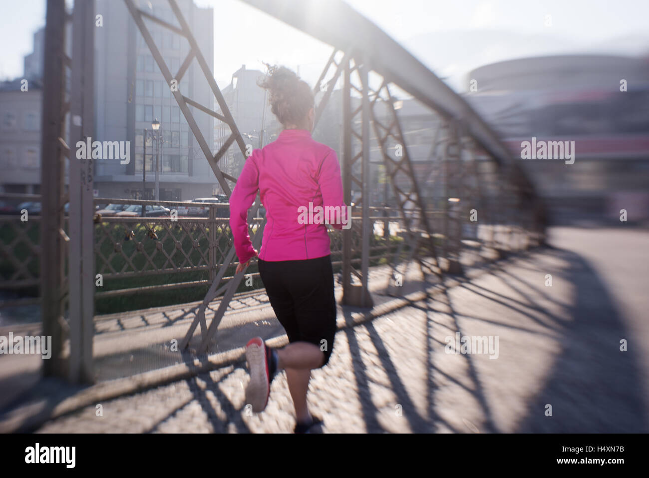 sporty woman running on sidewalk at early morning jogging with city ...