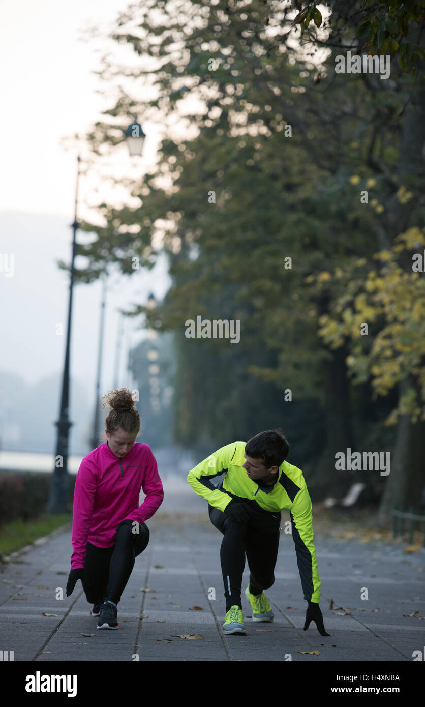 jogging couple warming up and stretching before morning running in the ...