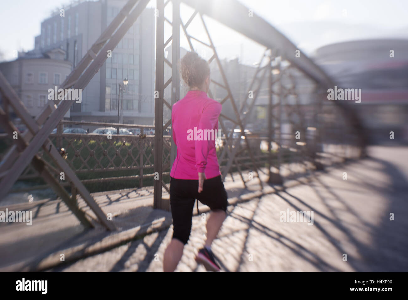 sporty woman running on sidewalk at early morning jogging with city ...