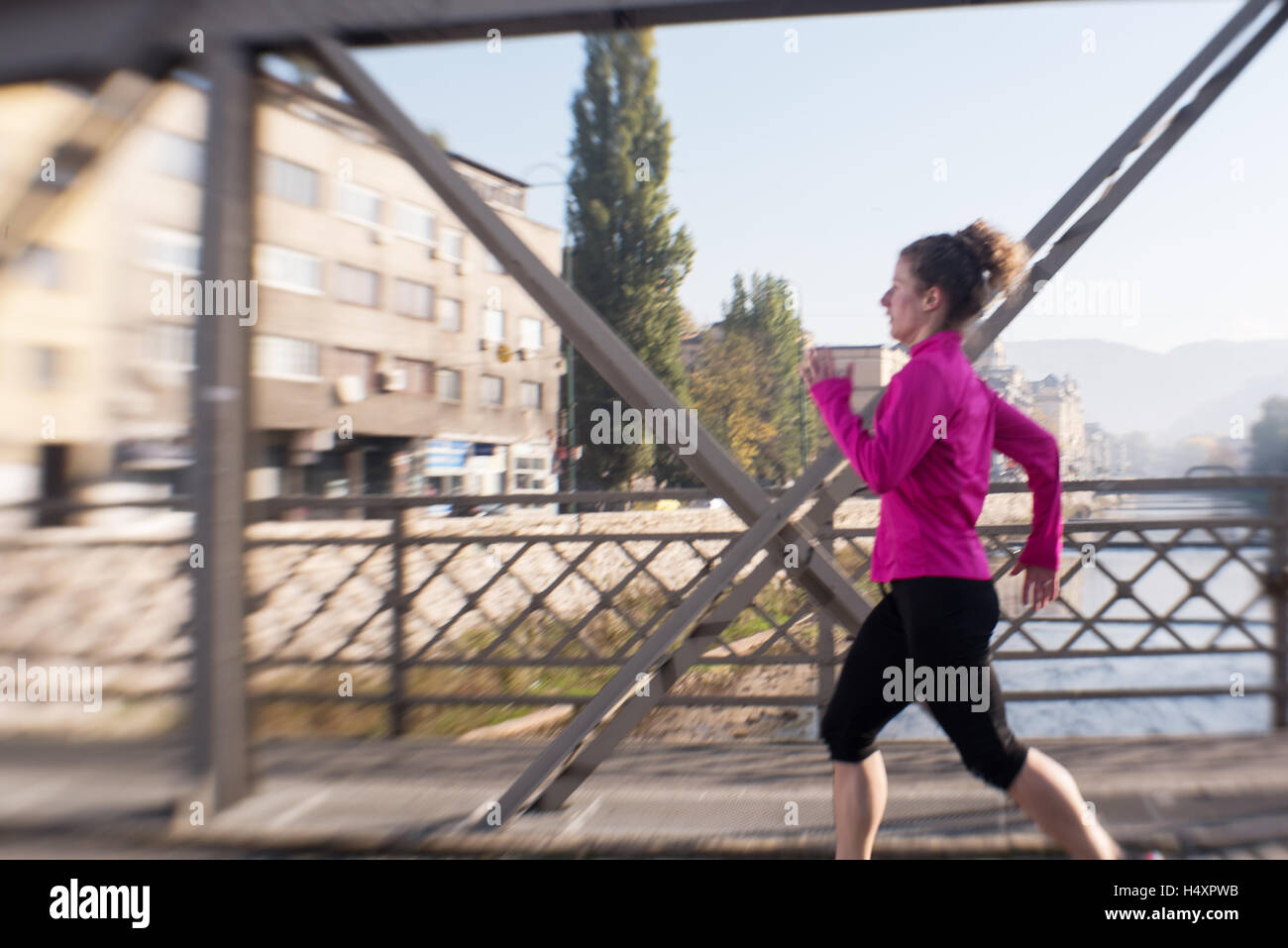 sporty woman running on sidewalk at early morning jogging with city ...