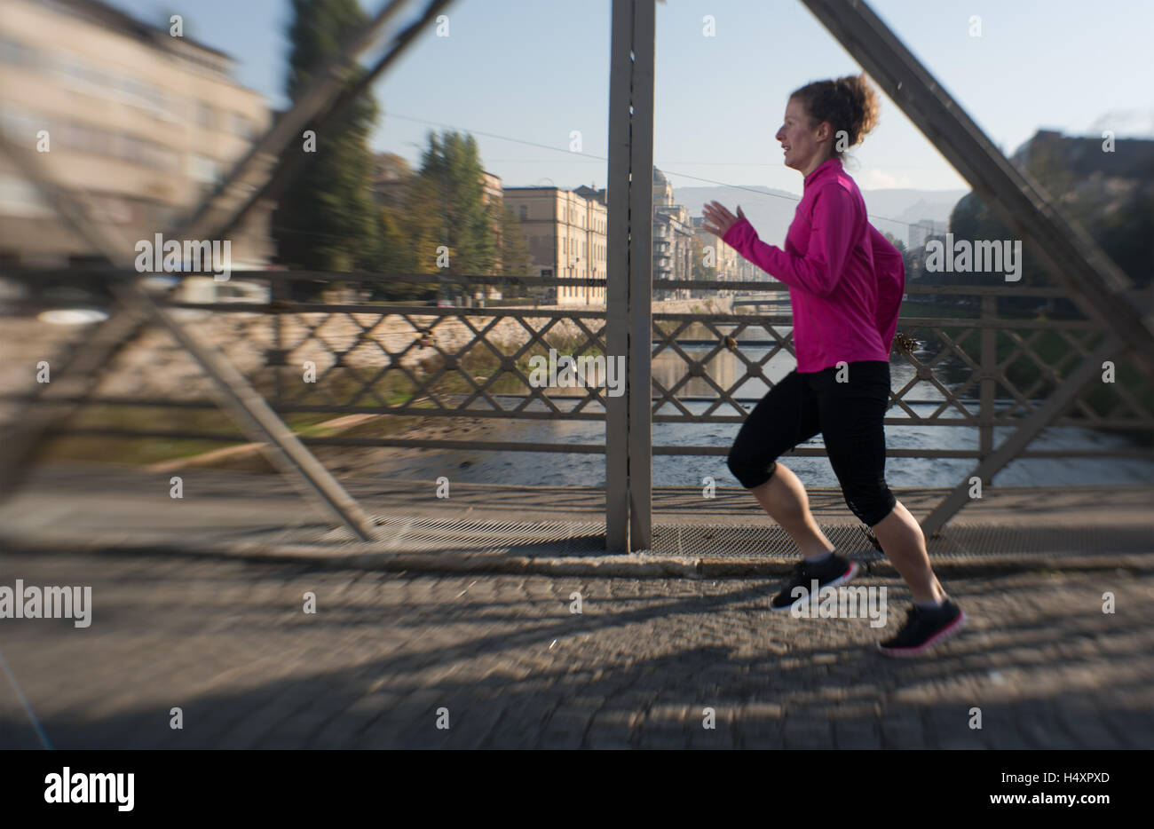 sporty woman running on sidewalk at early morning jogging with city ...