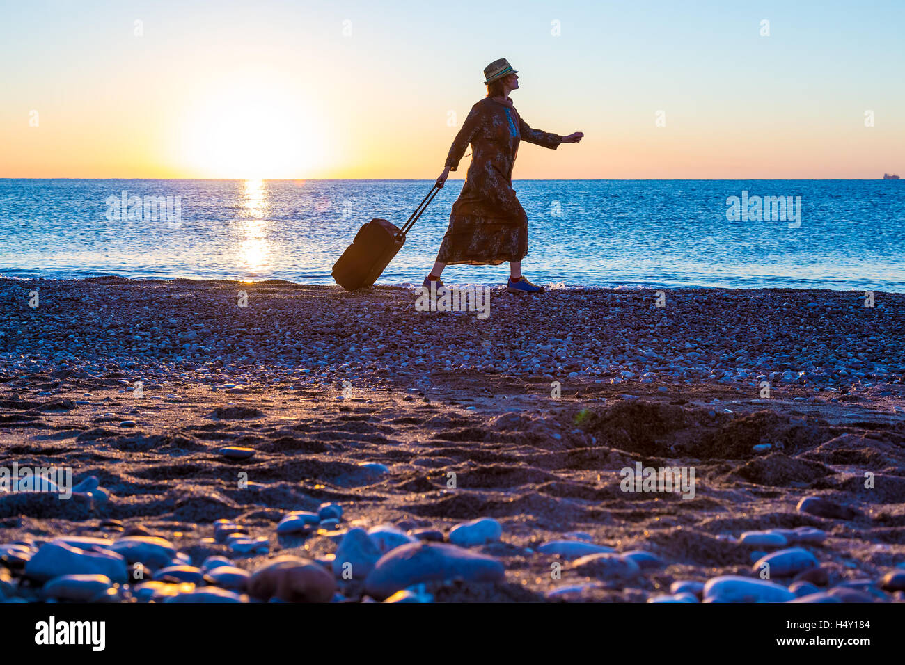 Woman walking on beach luggage hi-res stock photography and images - Alamy