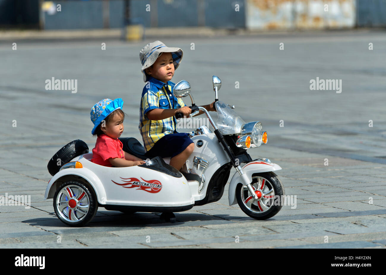 Brother and sister riding an electric toy motorcycle combination on ...