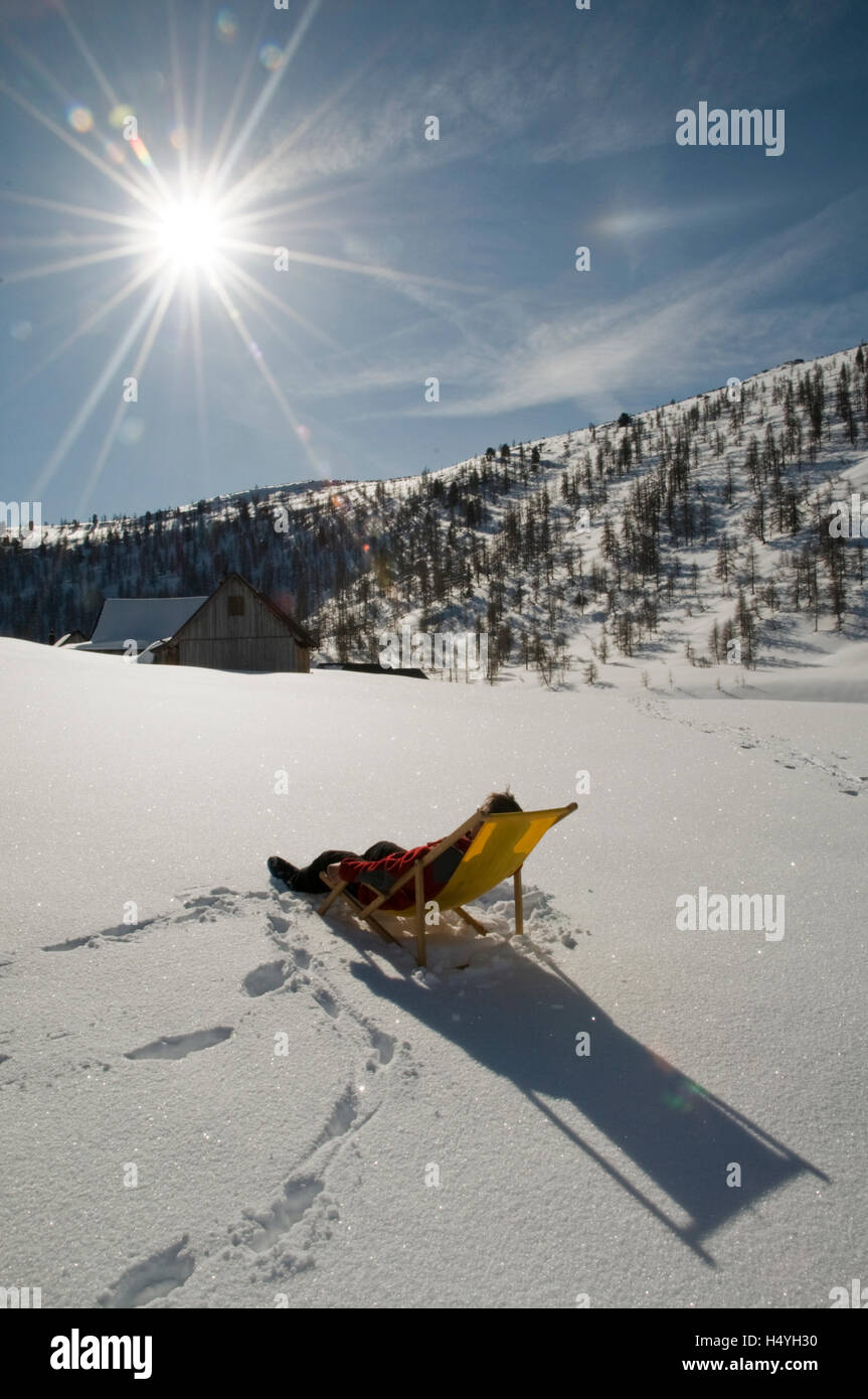 Sunbathing in a deck chair in the snow, Woerschach, Styria, Austria ...