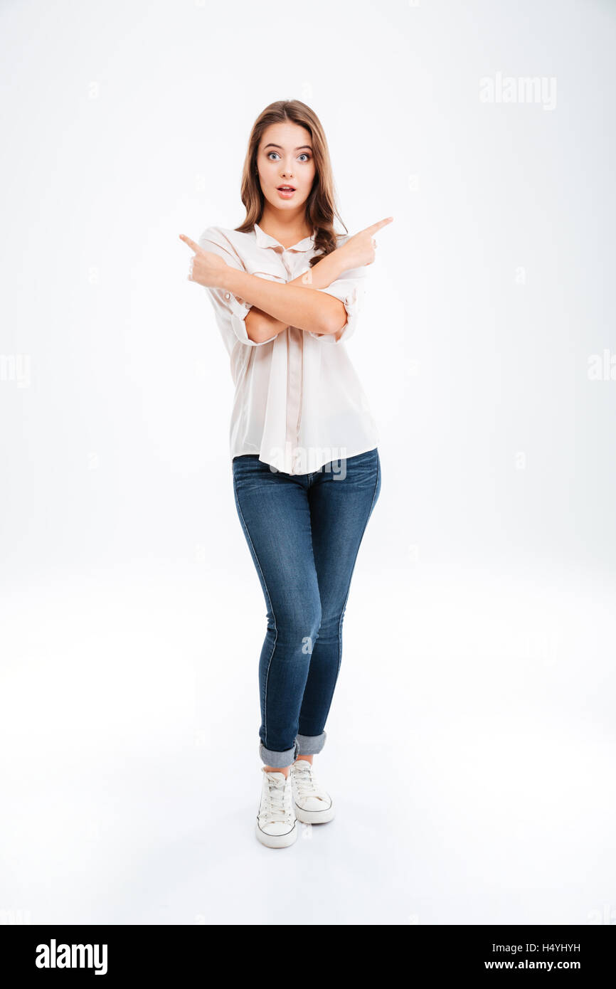Attractive young woman standing and pointing left and right over white ...