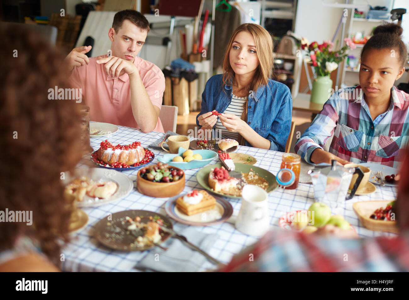 Friendly young people having conversation by festive dinner Stock Photo ...