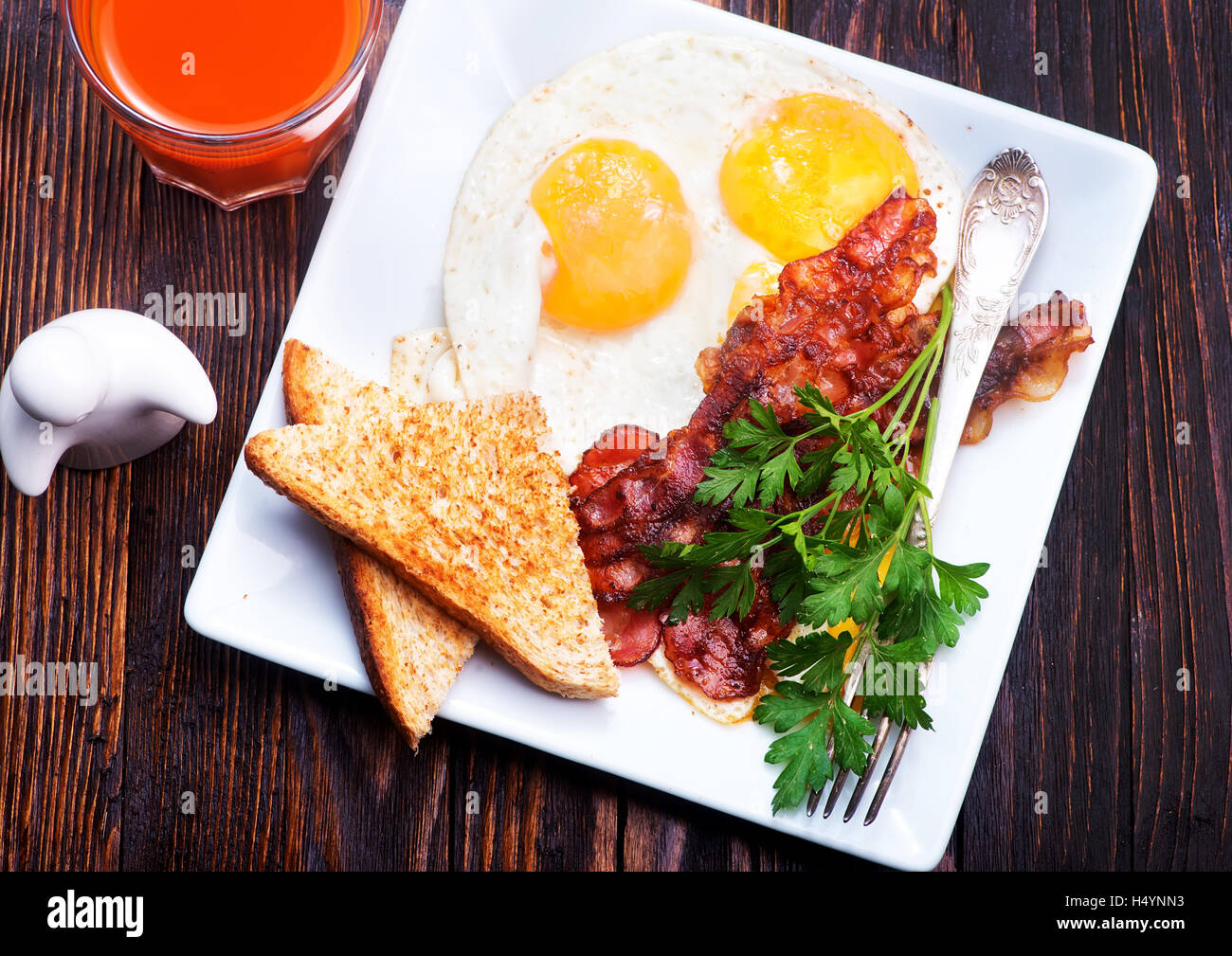 Breakfast on a table, fried bacon and eggs on plate Stock Photo - Alamy