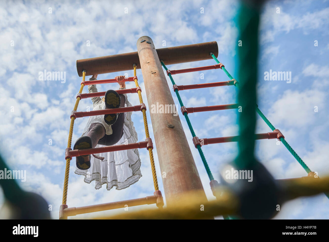 Portrait of Happy little blond girl playing on a rope web playground ...