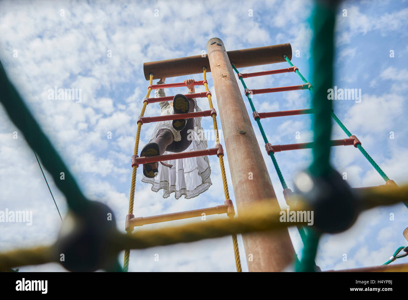 Portrait of Happy little blond girl playing on a rope web playground ...