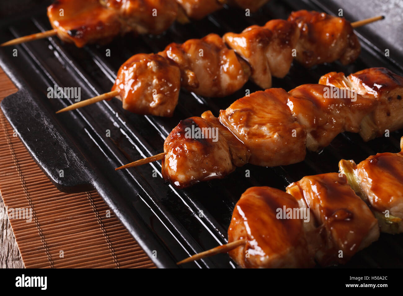 Japanese yakitori skewers of chicken on a grill pan. Horizontal close ...