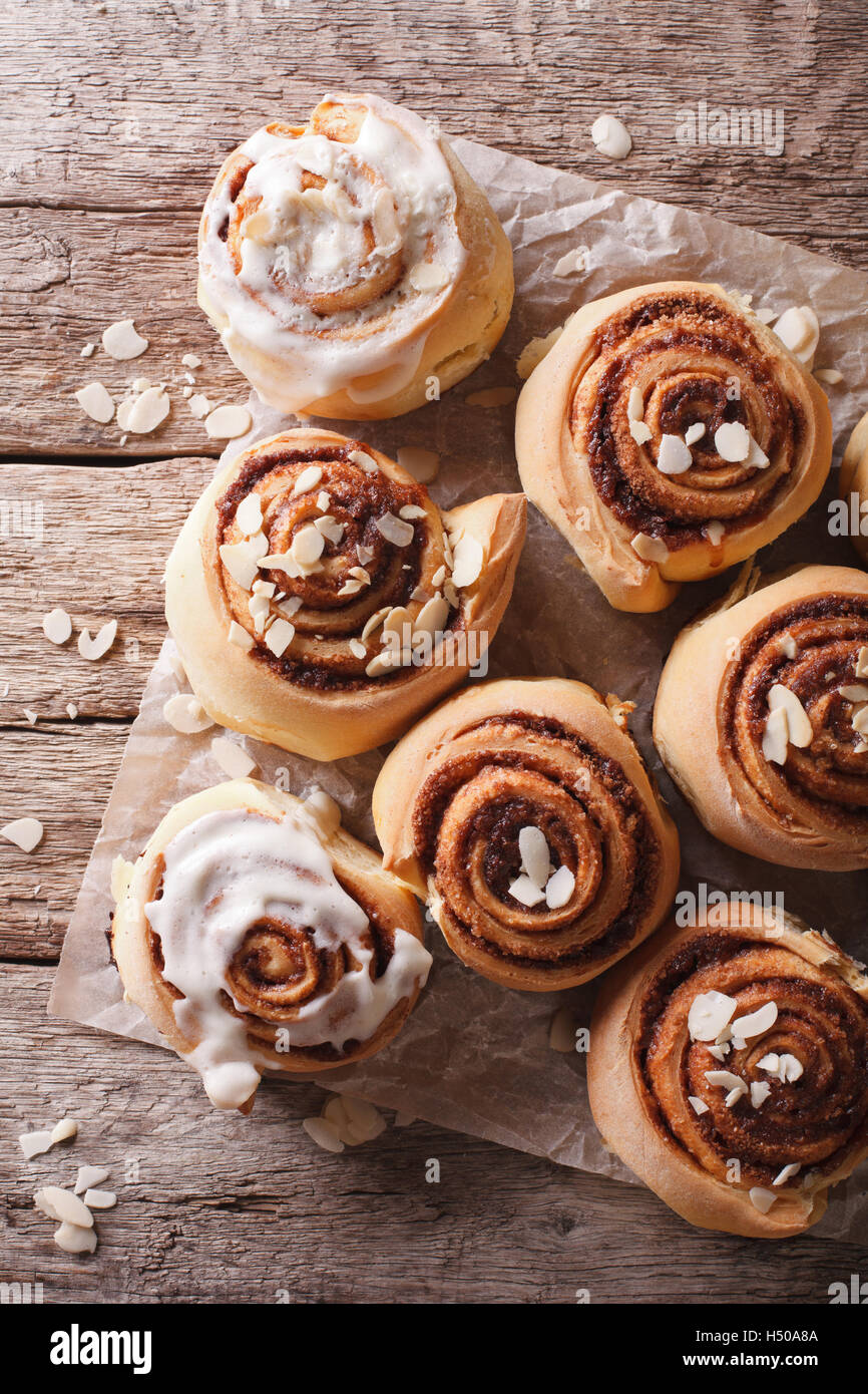 Glazed Cinnamon rolls with almond close up on the table. vertical top ...