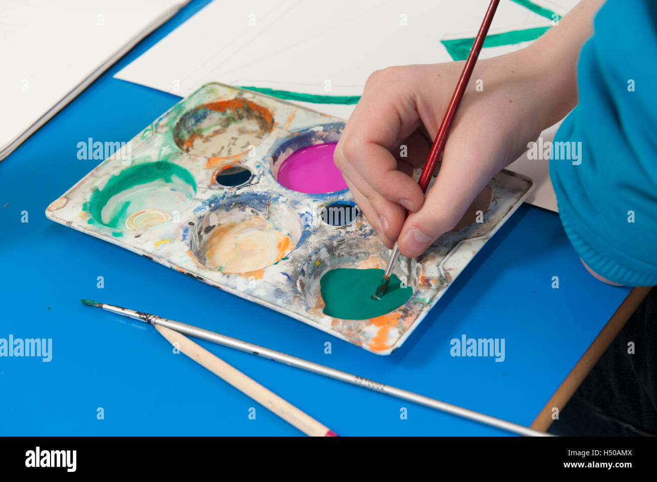 Girls hand with paintbrush in palette Stock Photo - Alamy
