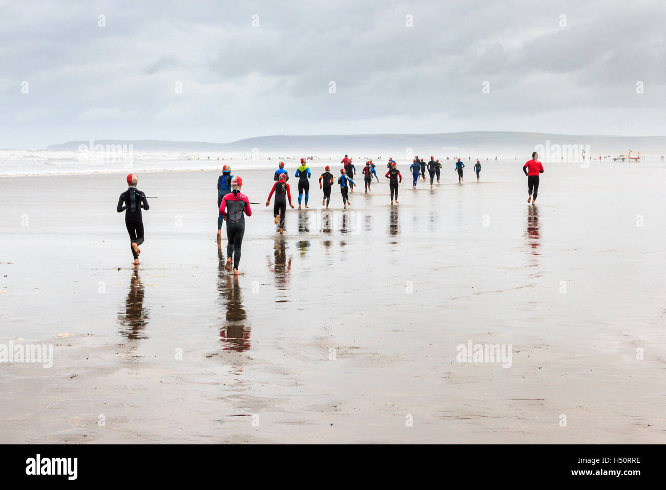 Surfing students jogging along the windswept beach at Westward Ho ...