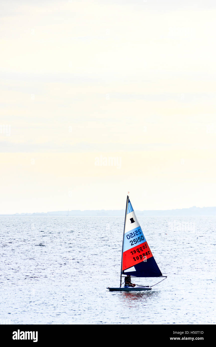 A single sailing dinghy in the evening on Weymouth Bay, Dorset, England ...
