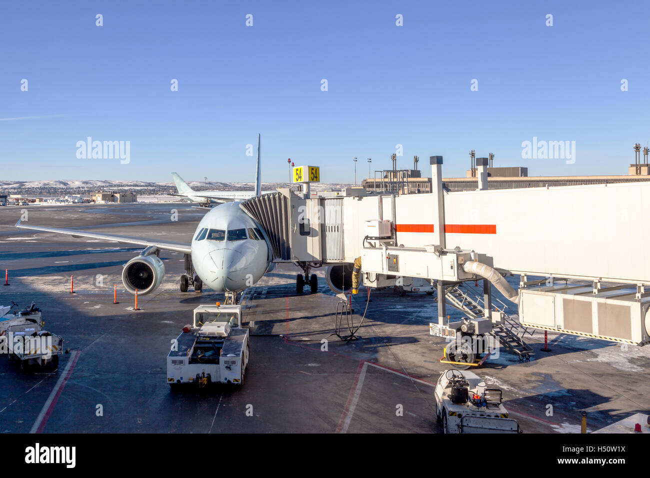 A passenger plane connected to a jet bridge being serviced by at ...