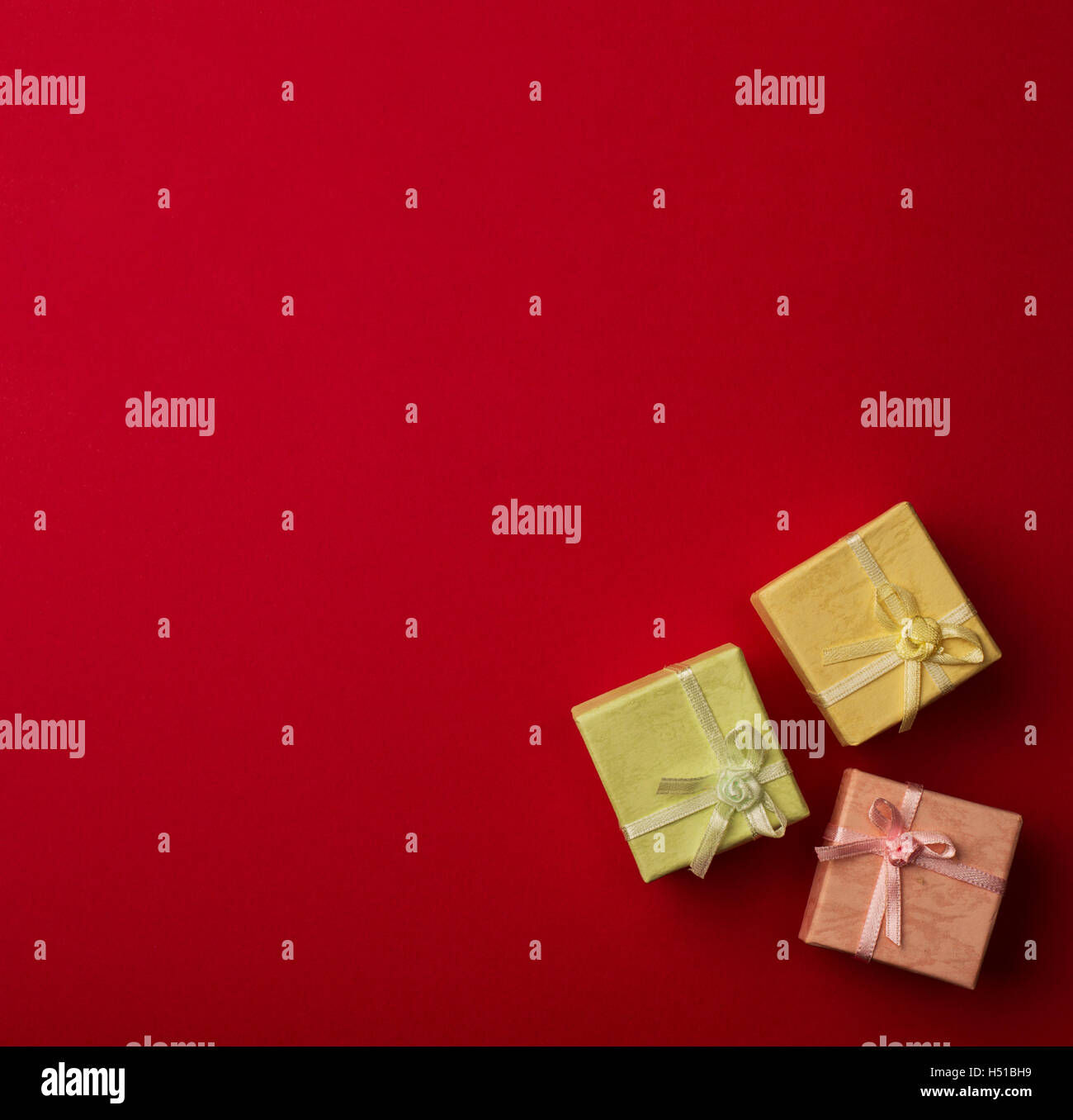 Top view of three small cardboard rectangular gift boxes on red paper ...