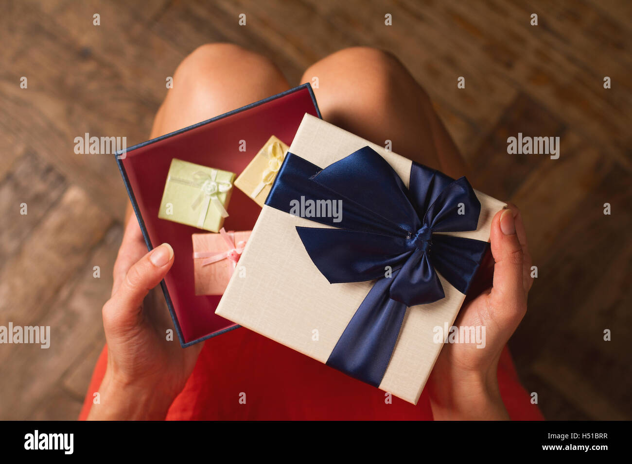 Top view woman opening a present with blue ribbon with three gift boxes ...
