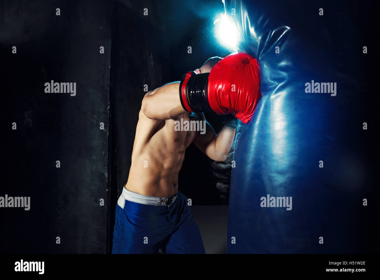Male Athlete boxer punching a punching bag with dramatic edgy lighting ...