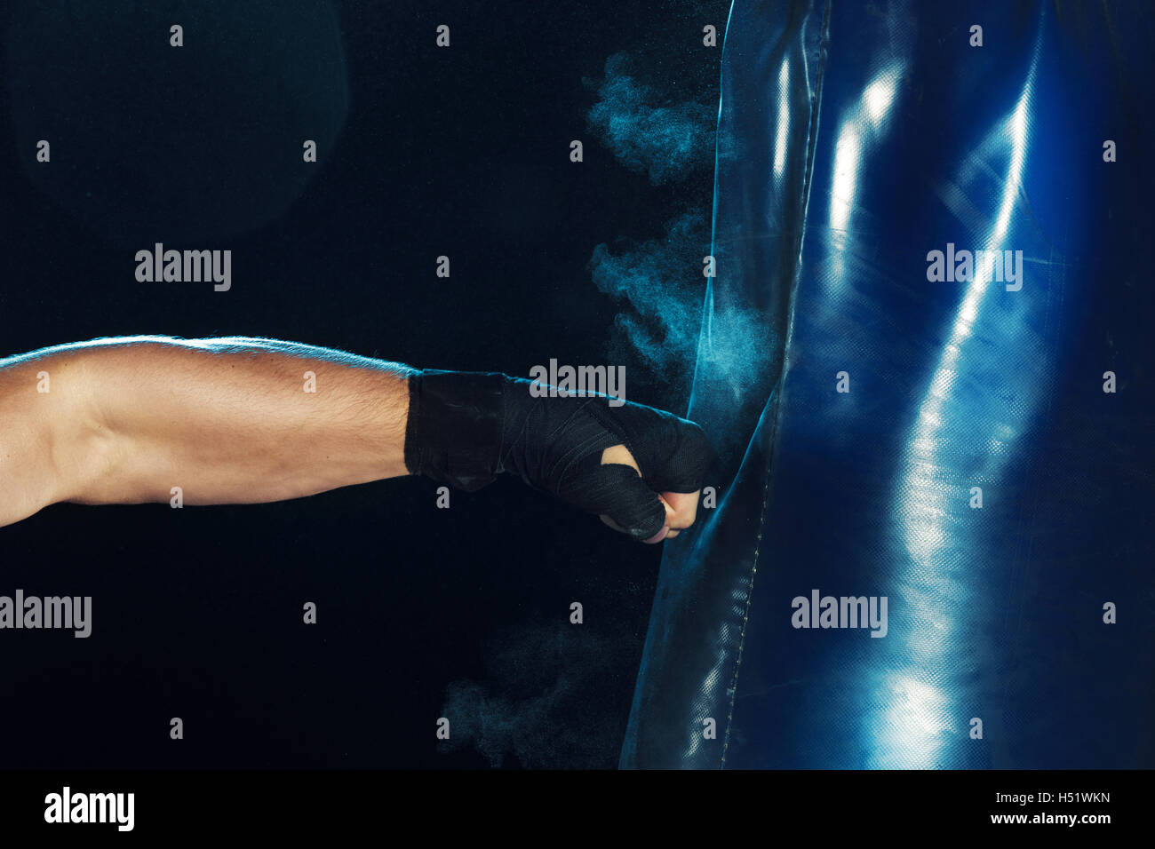Male Athlete boxer punching a punching bag with dramatic edgy lighting ...