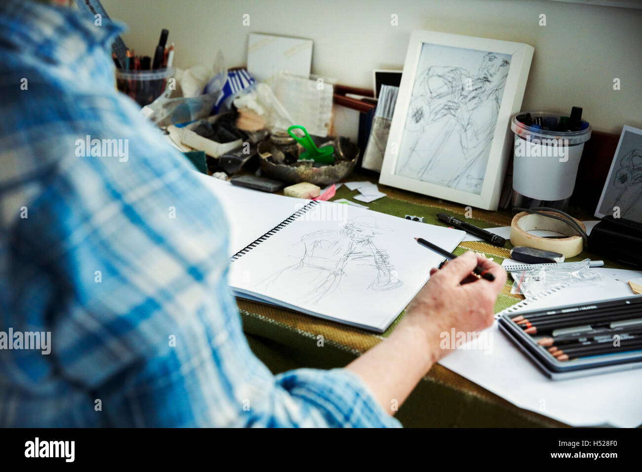 An artist working, holding a pencil over a sketch in progress in open ...