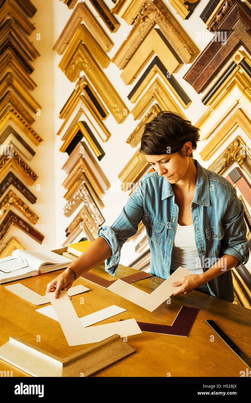 Woman working at a picture framers, a large selection of frames on the ...