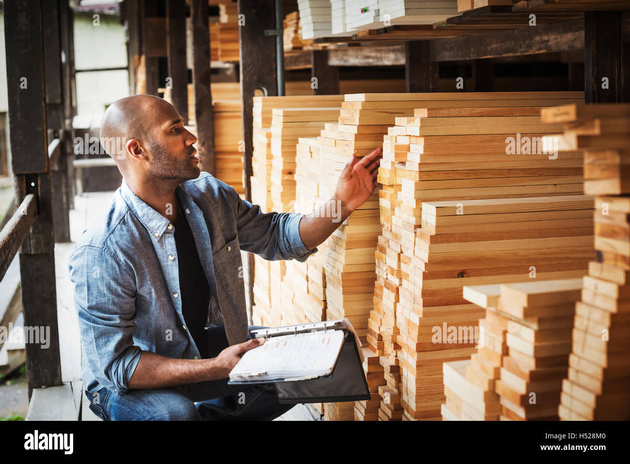 Man in a lumber yard, holding a folder, checking wood Stock Photo - Alamy