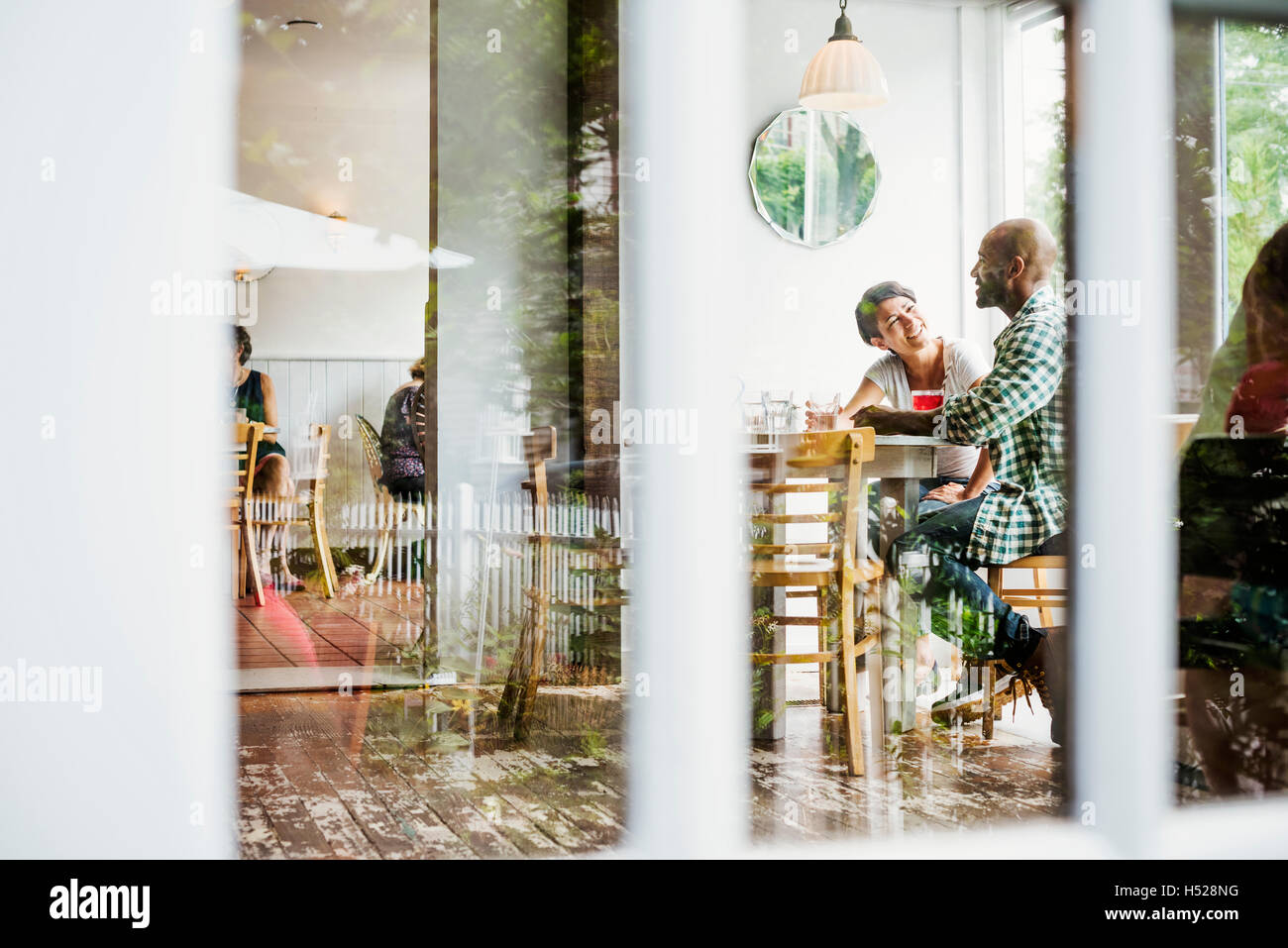 View through a window into a cafe, people sitting at tables Stock Photo ...