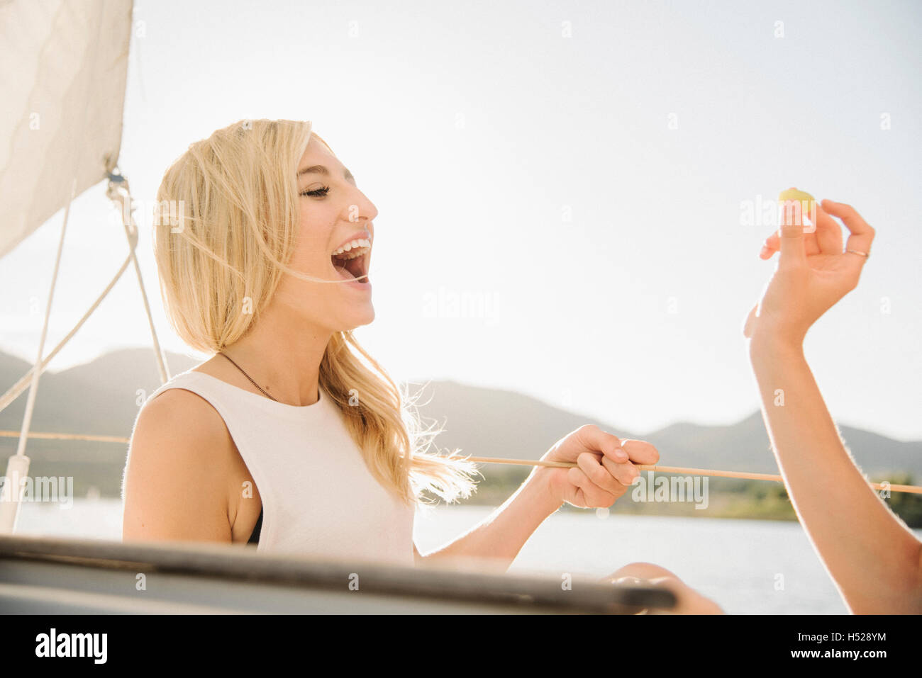 Blond teenage girl on a sail boat, laughing Stock Photo - Alamy