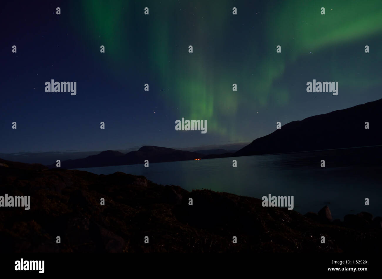 beautiful aurora borealis dancing over mountain and fjord landscape on ...