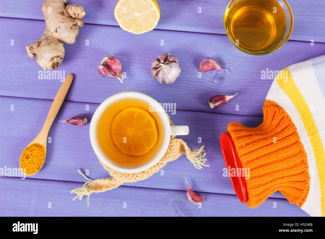 Hot water bottle, cup of tea with lemon and ingredients for preparation ...
