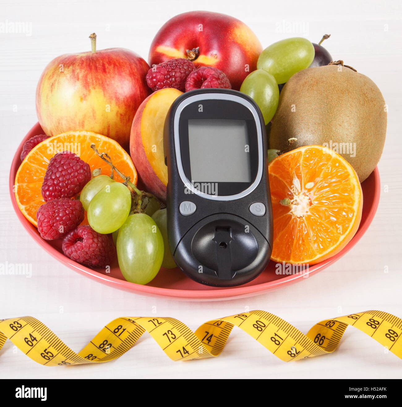 Glucose meter for measuring and checking sugar level, fruits on plate ...