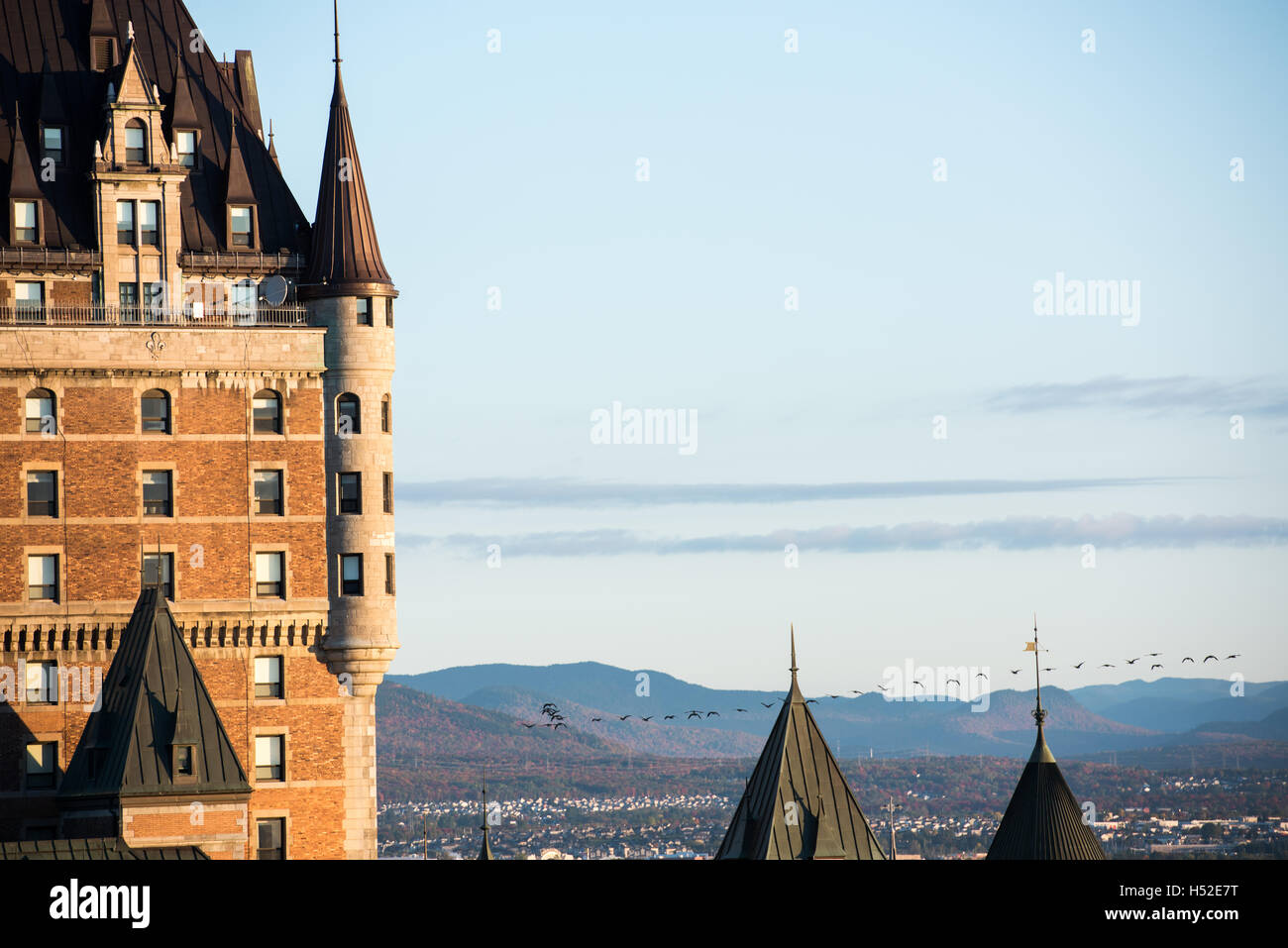 Chateau Frontenac with mountains in the background and a flock of birds ...