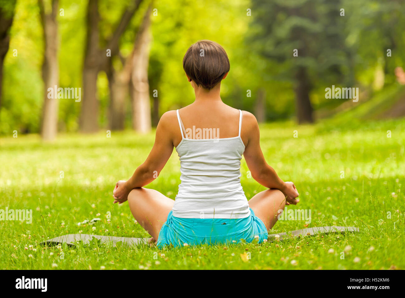 Woman meditating and doing yoga in park back Stock Photo - Alamy